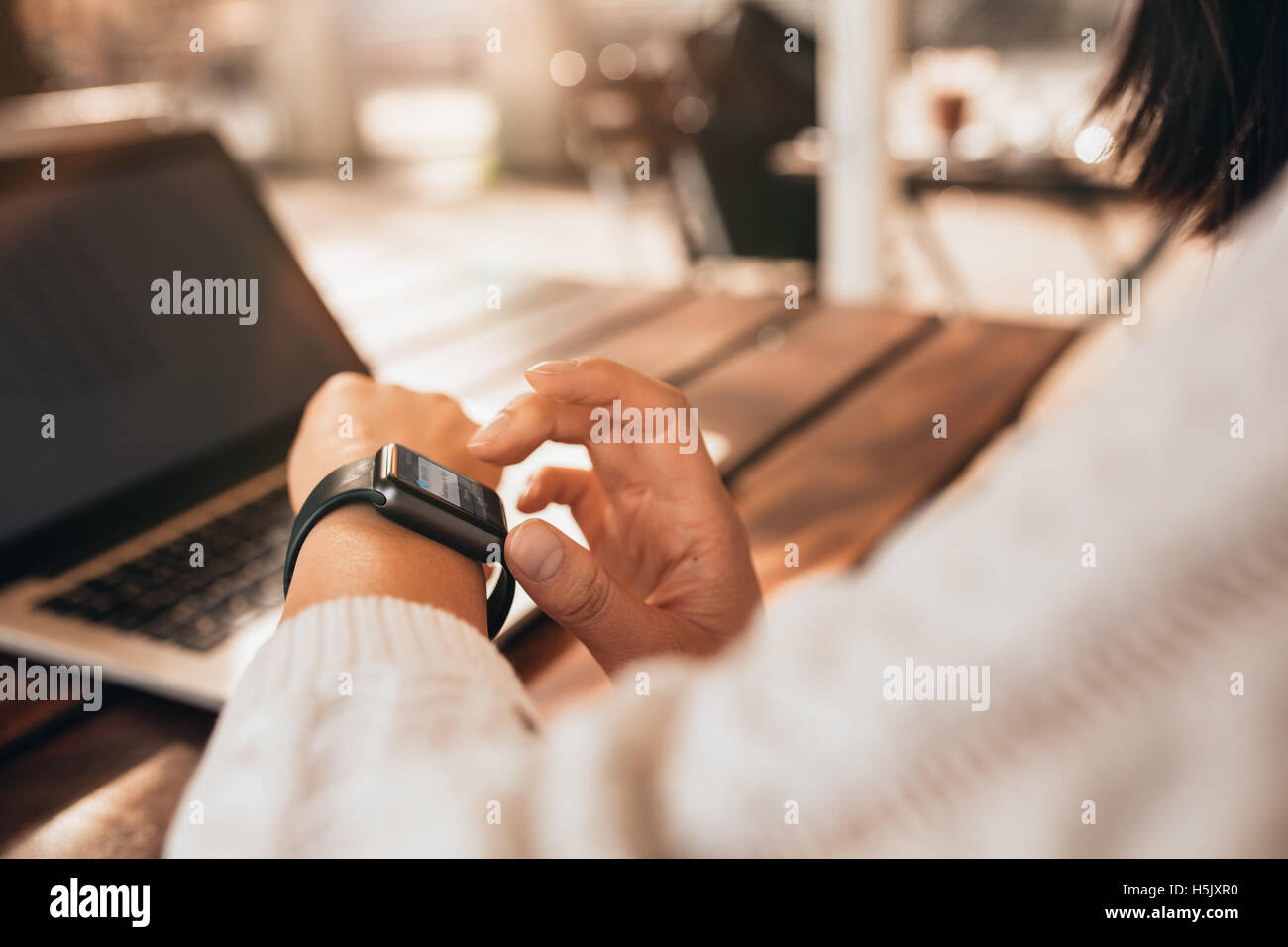 Close up of young woman using smartwatch at a cafe. Female sitting at a ...