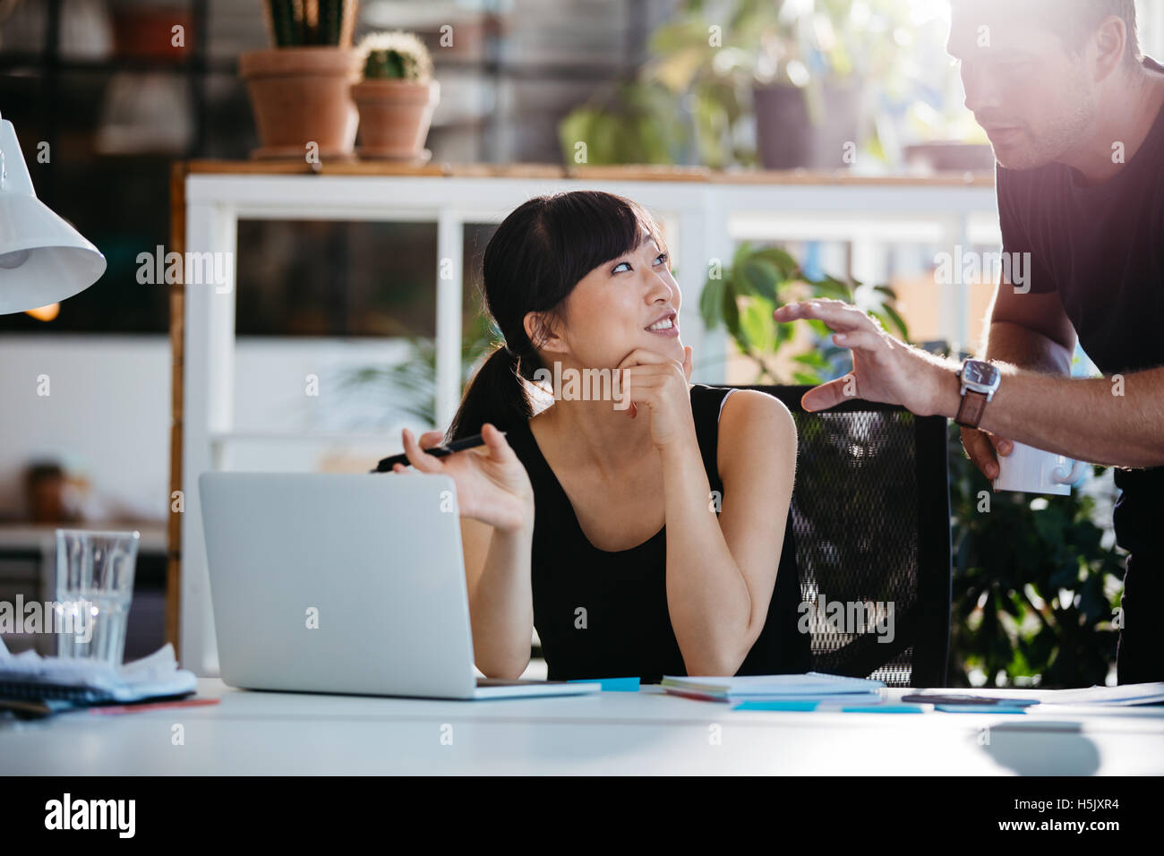 Smiling businesswoman talking with partner while sitting at her desk ...