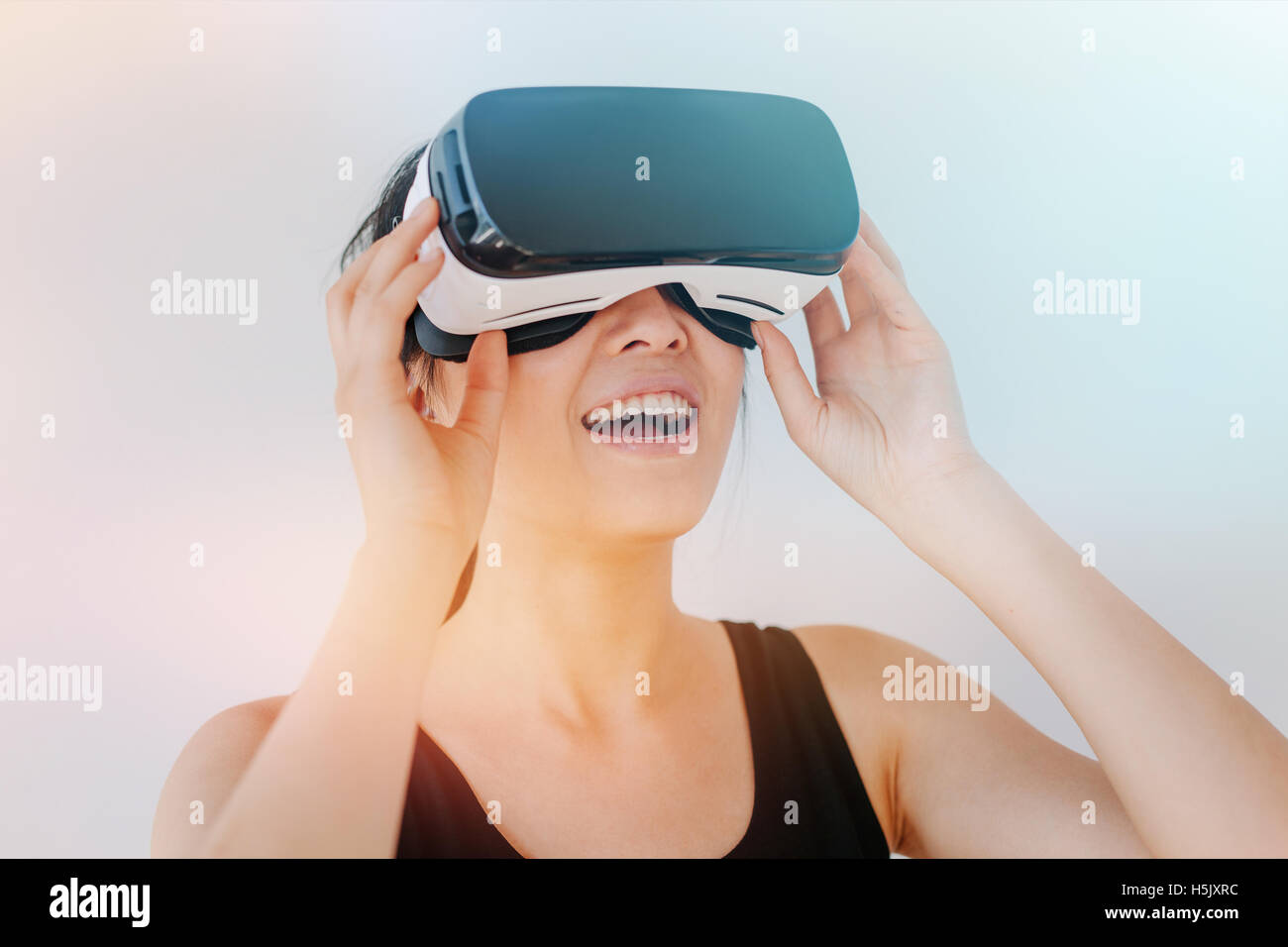 Close up shot of smiling young woman using the VR goggles against grey ...