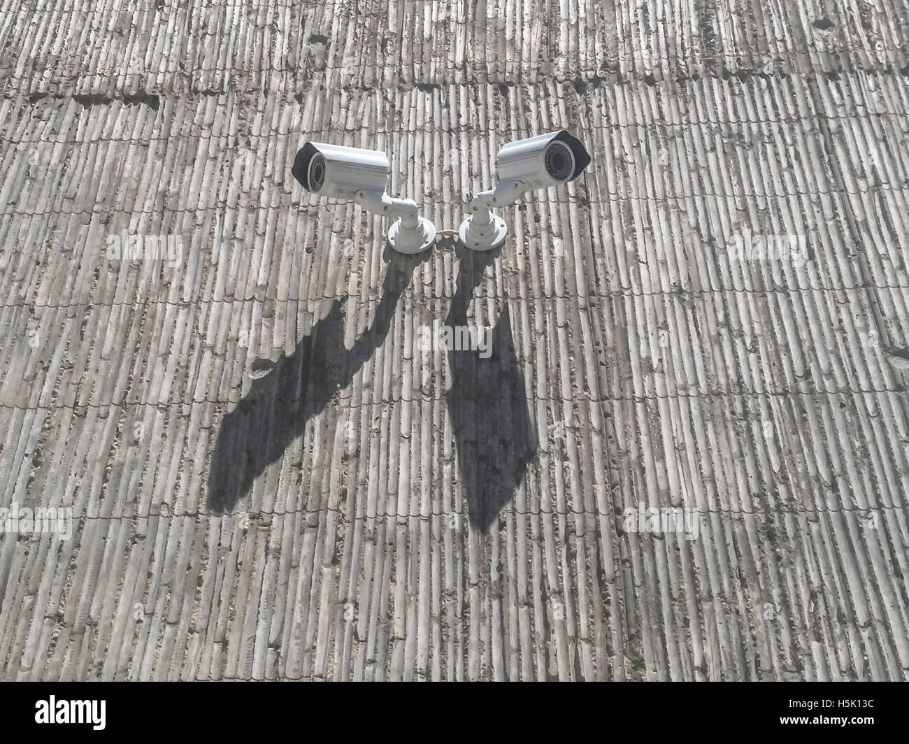 Two security cameras on grey concrete building wall Stock Photo - Alamy