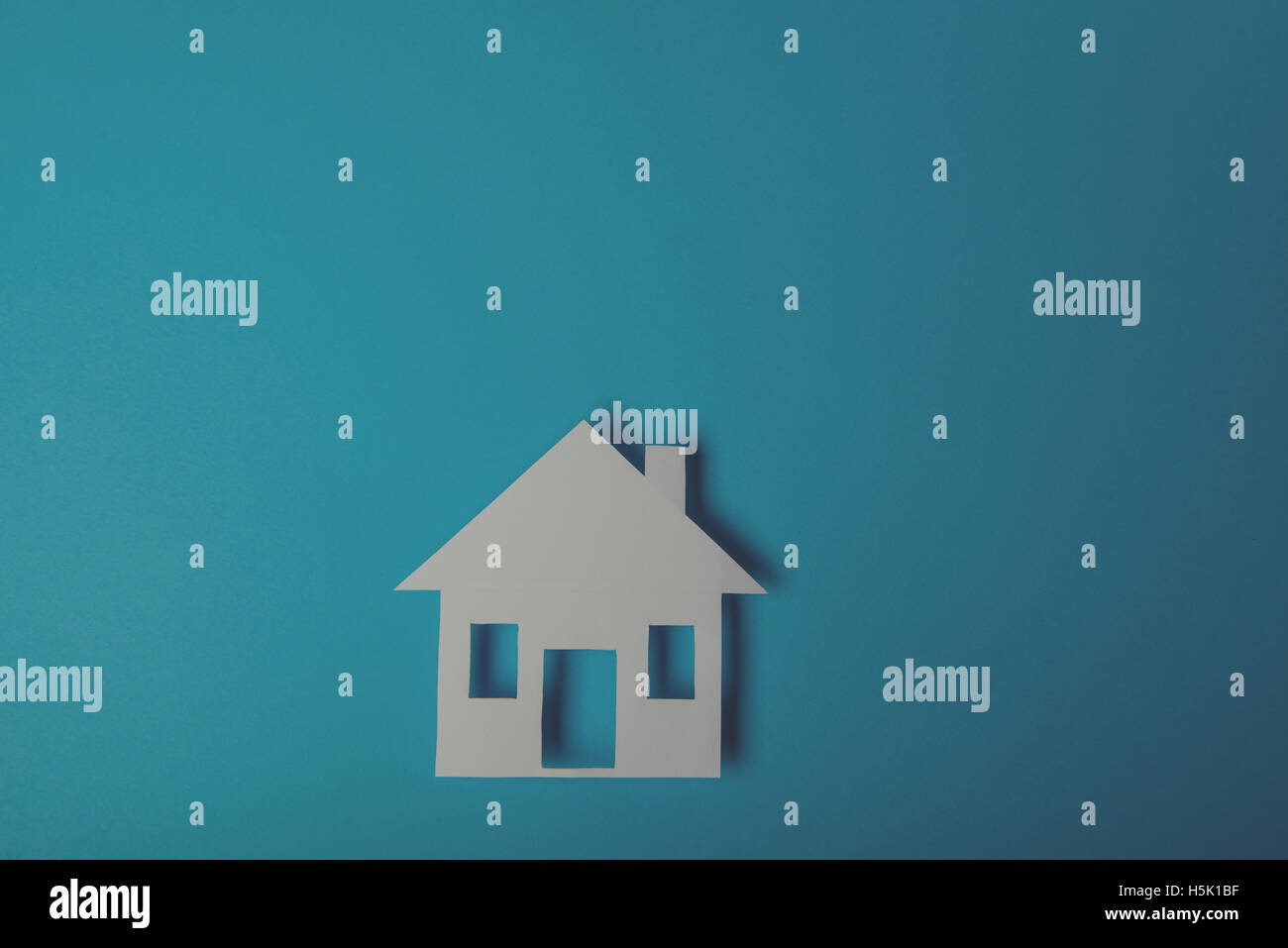 House shaped paper cutout on on blue background Stock Photo - Alamy