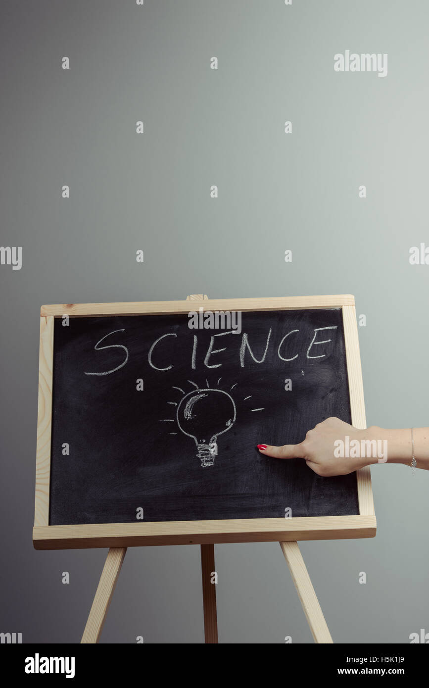 A teacher writing science, drawing chemistry elements on dark ...