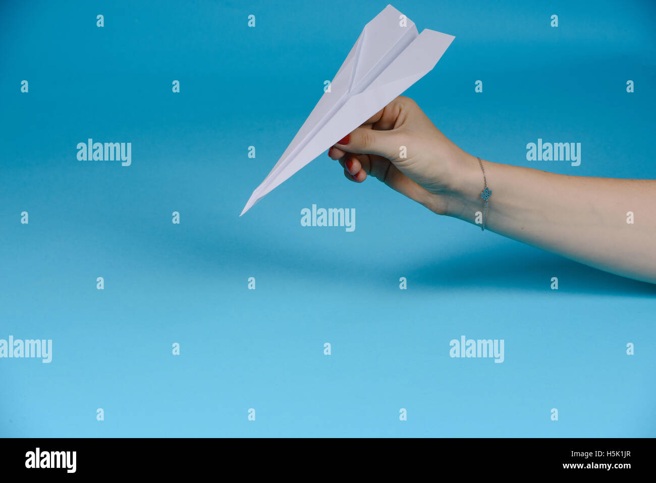 Paper plane in female hand on a blue background Stock Photo - Alamy