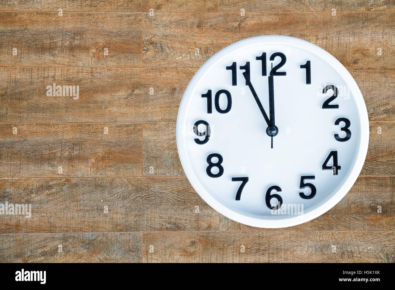 Clock show 5 minute to 12 am or pm on wood background with copy space ...