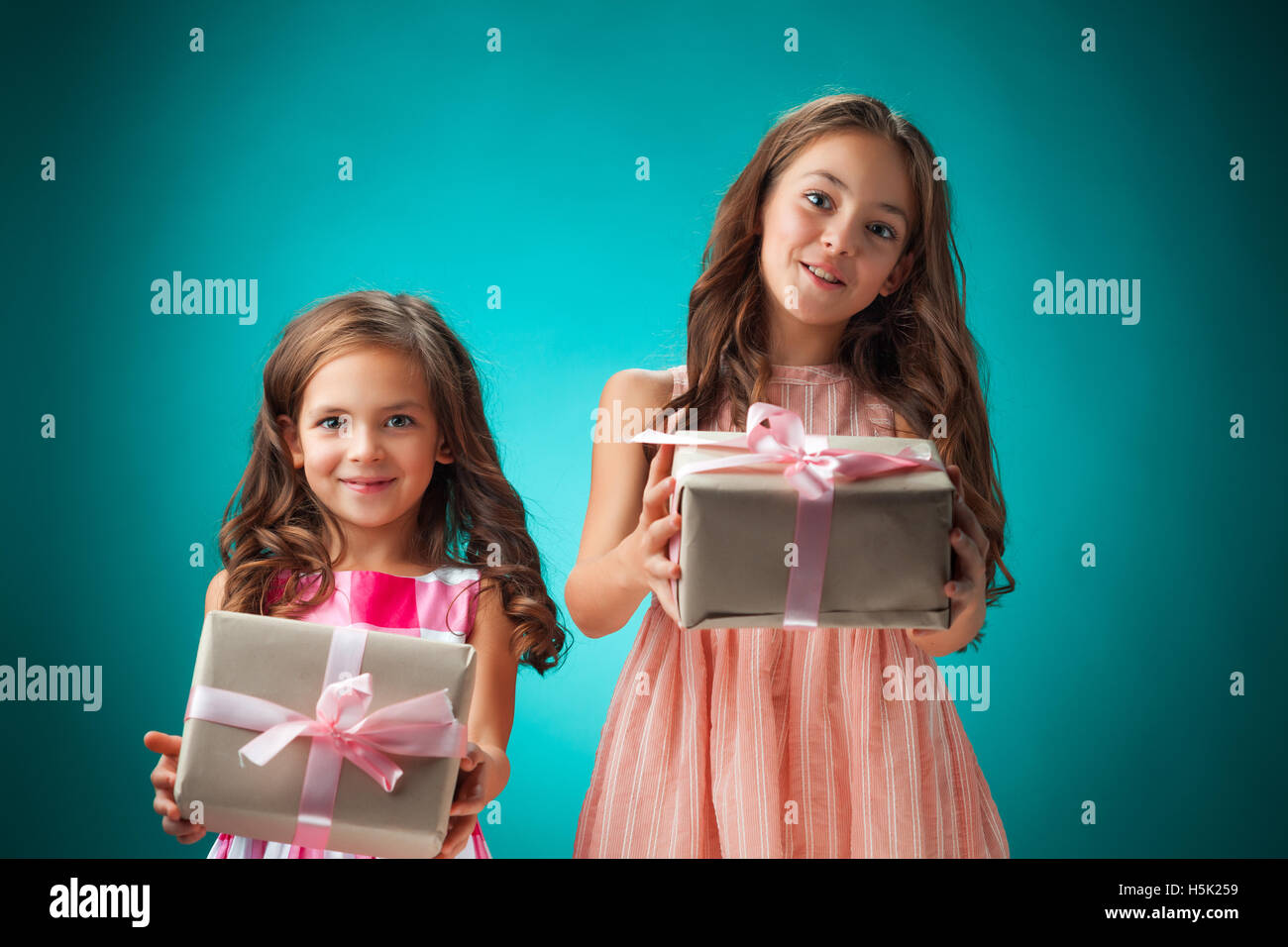 The two cute cheerful little girls on blue background Stock Photo - Alamy
