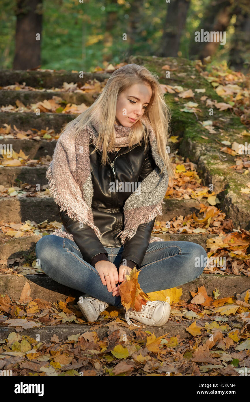sad girl in autumn park sitting, toned image Stock Photo - Alamy
