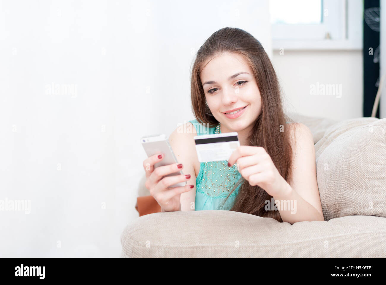 Happy girl on the couch at home in the living room Stock Photo - Alamy