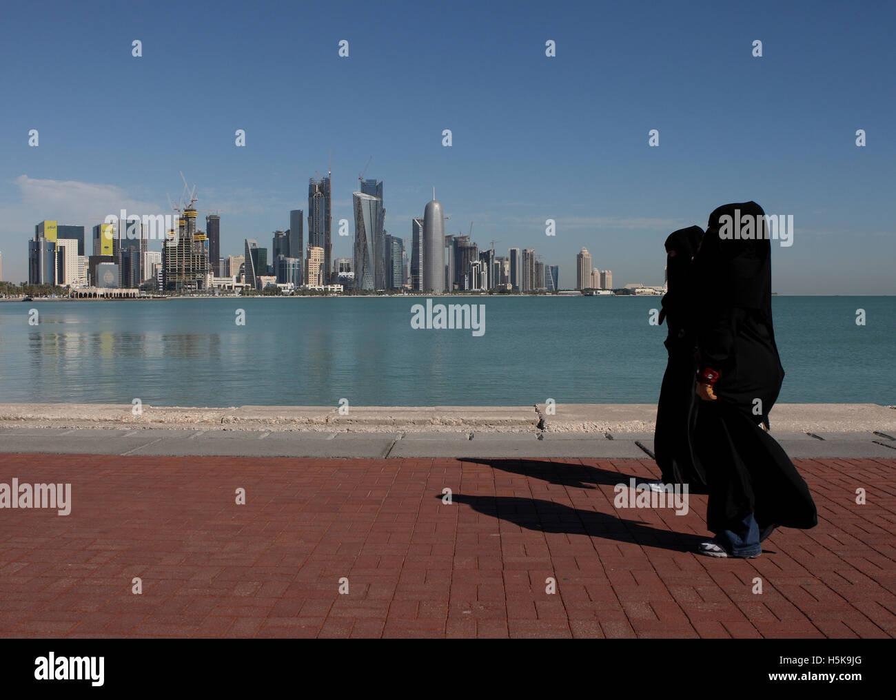 Arabian women wearing traditional black robes walking along the ...