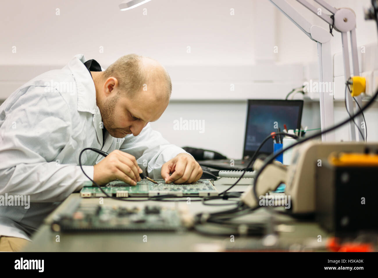 Technician fixing motherboard by soldering chips Stock Photo - Alamy