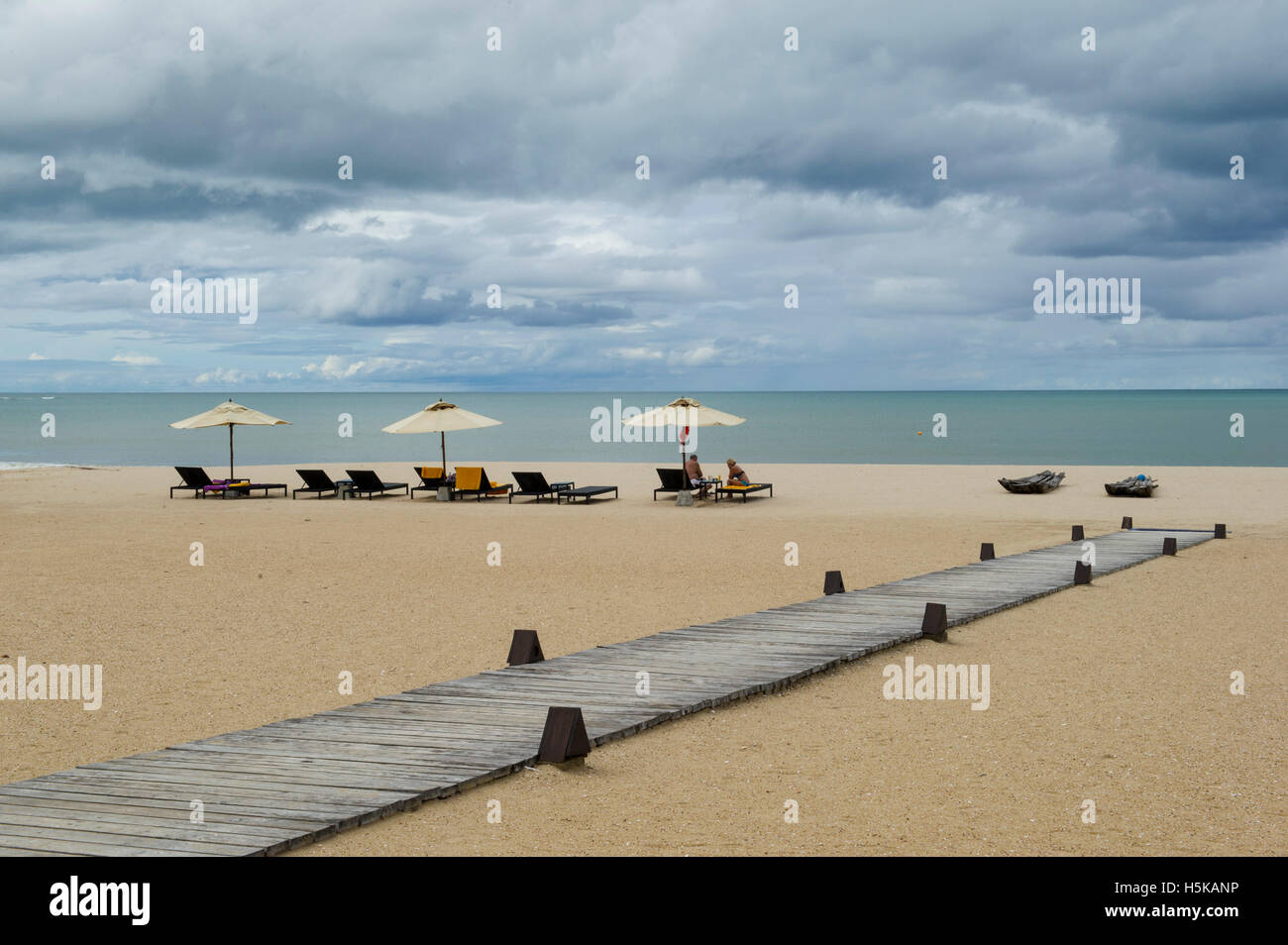 Tourists sitting on a sandy beach in front of one of the resorts in ...
