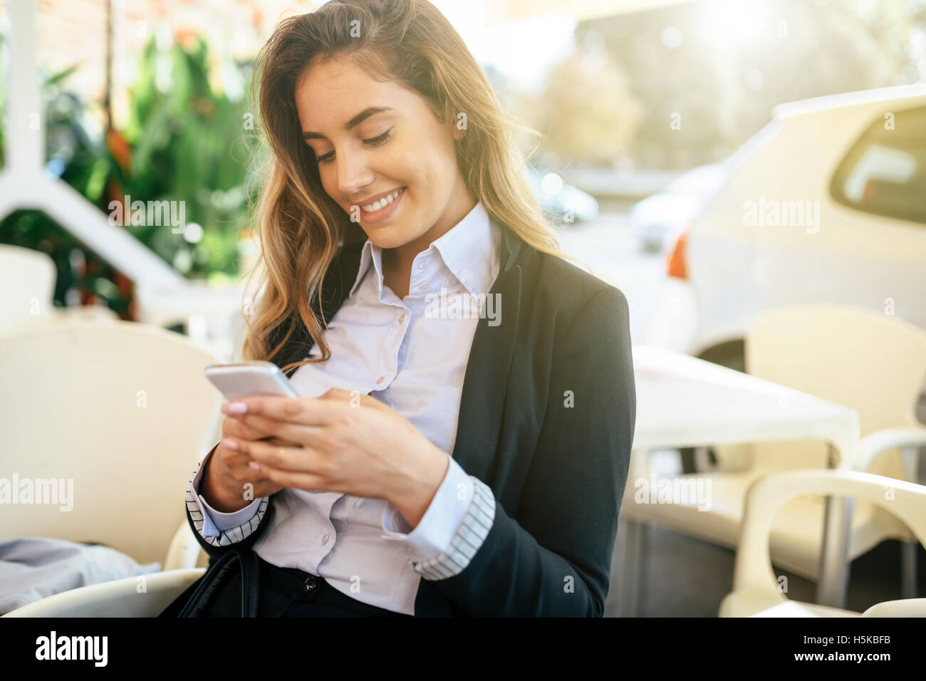 Happy businesswoman using phone outdoors Stock Photo - Alamy
