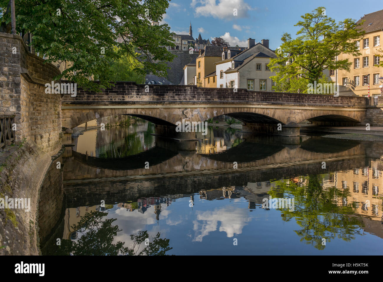 Stone bridge reflecting in the Alzette river in the city of Luxembourg ...