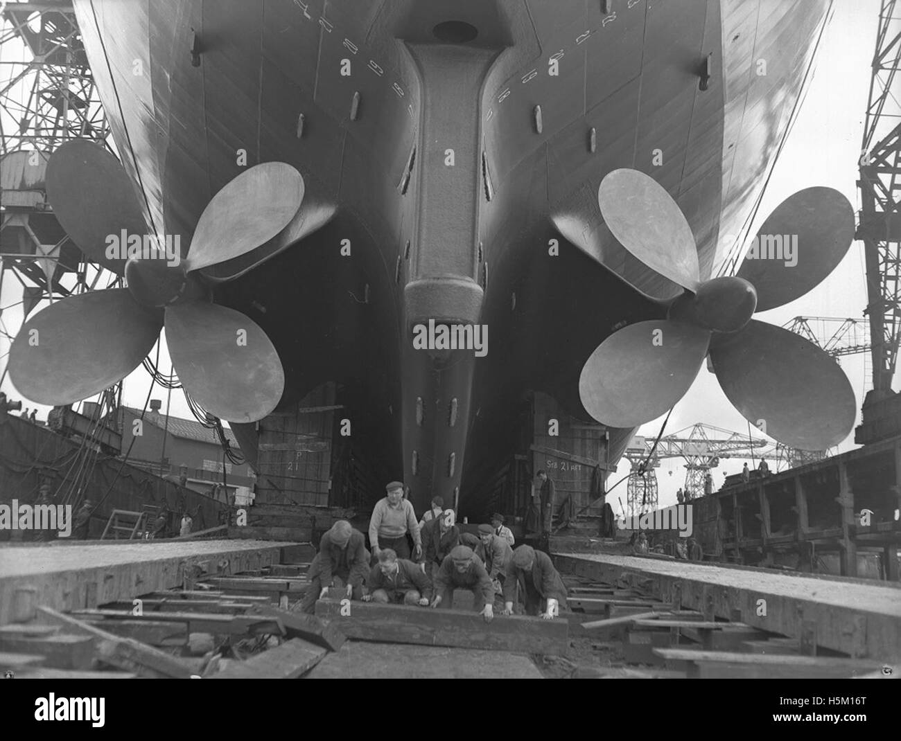 The image shows workers preparing the slipway for a ship launch at ...