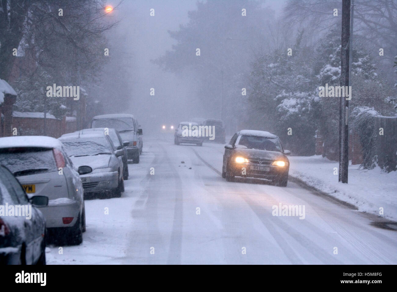 Cars driving in heavy snowfall with headlights and street lamps on ...