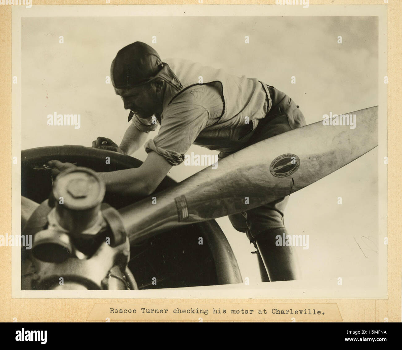 Roscoe Turner, an American aviator, is shown inspecting the engine of ...