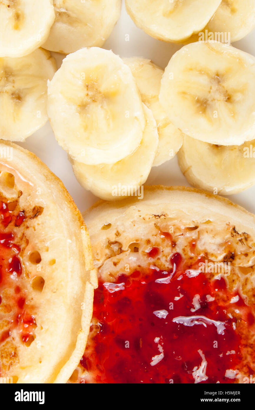 Close up shot of crumpets covered with strawberry jam with slices of ...