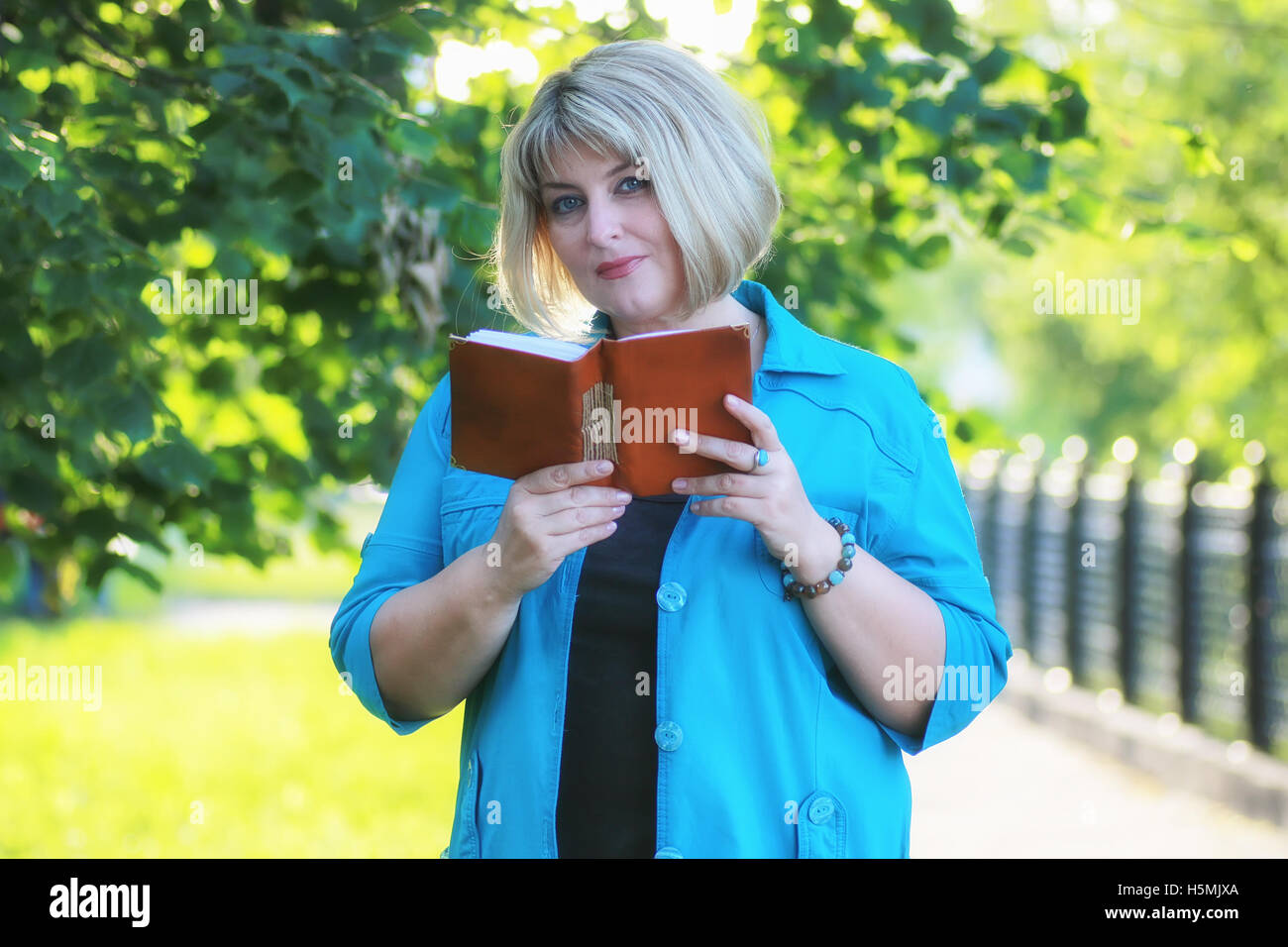 woman in the park green tree with book Stock Photo - Alamy