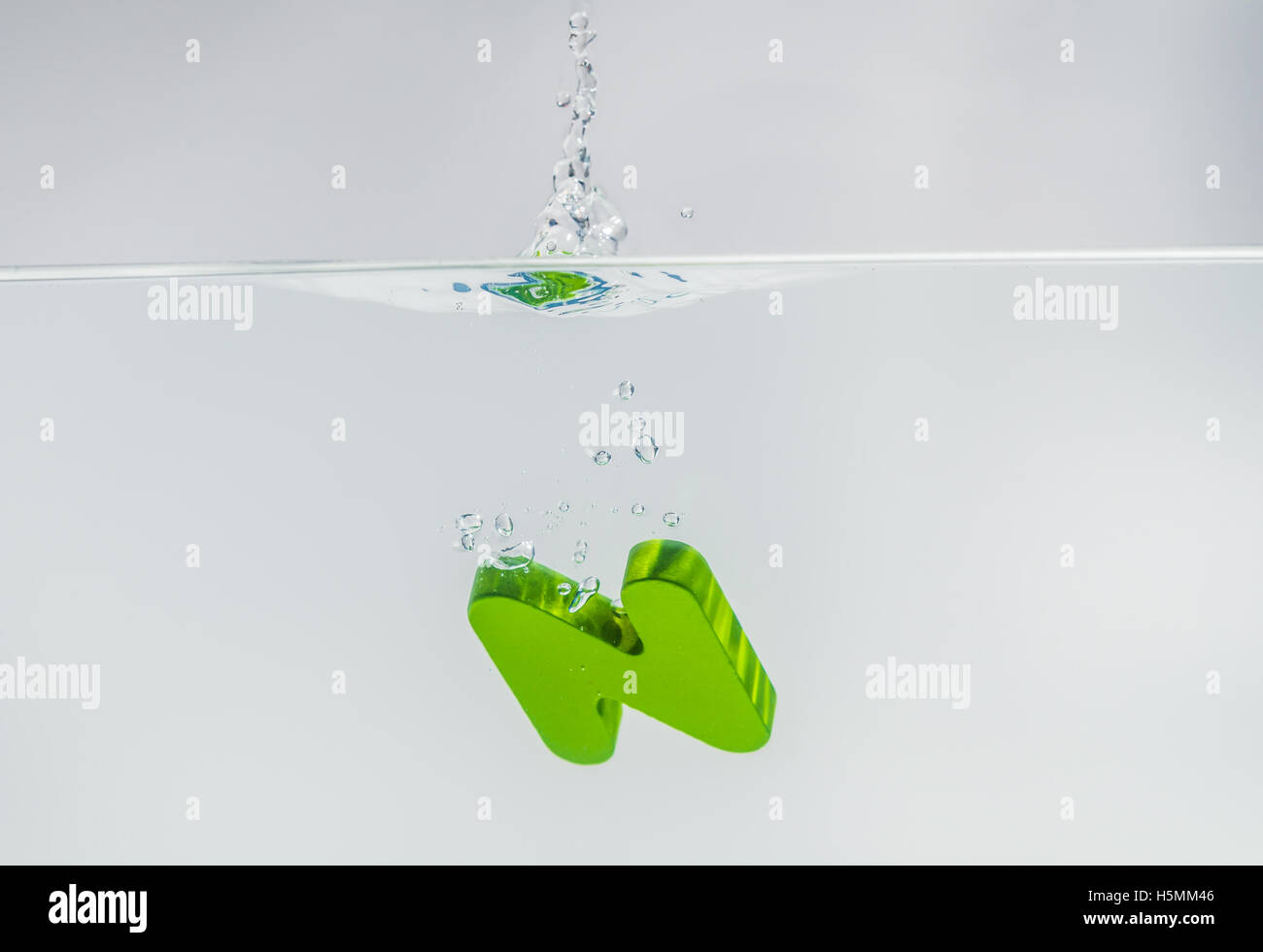 Green wooden alphabet N drop in the water with white background and ...
