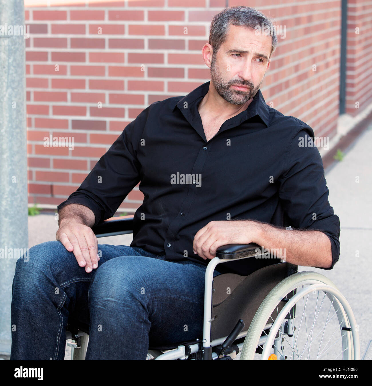 handsome man sitting in wheelchair and looking depressed Stock Photo ...