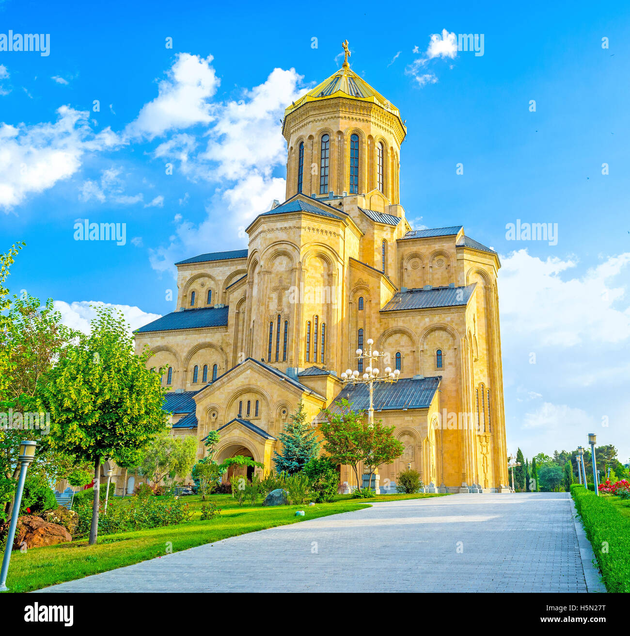 The beautiful stone Sameba Cathedral located on the hill among the lush ...