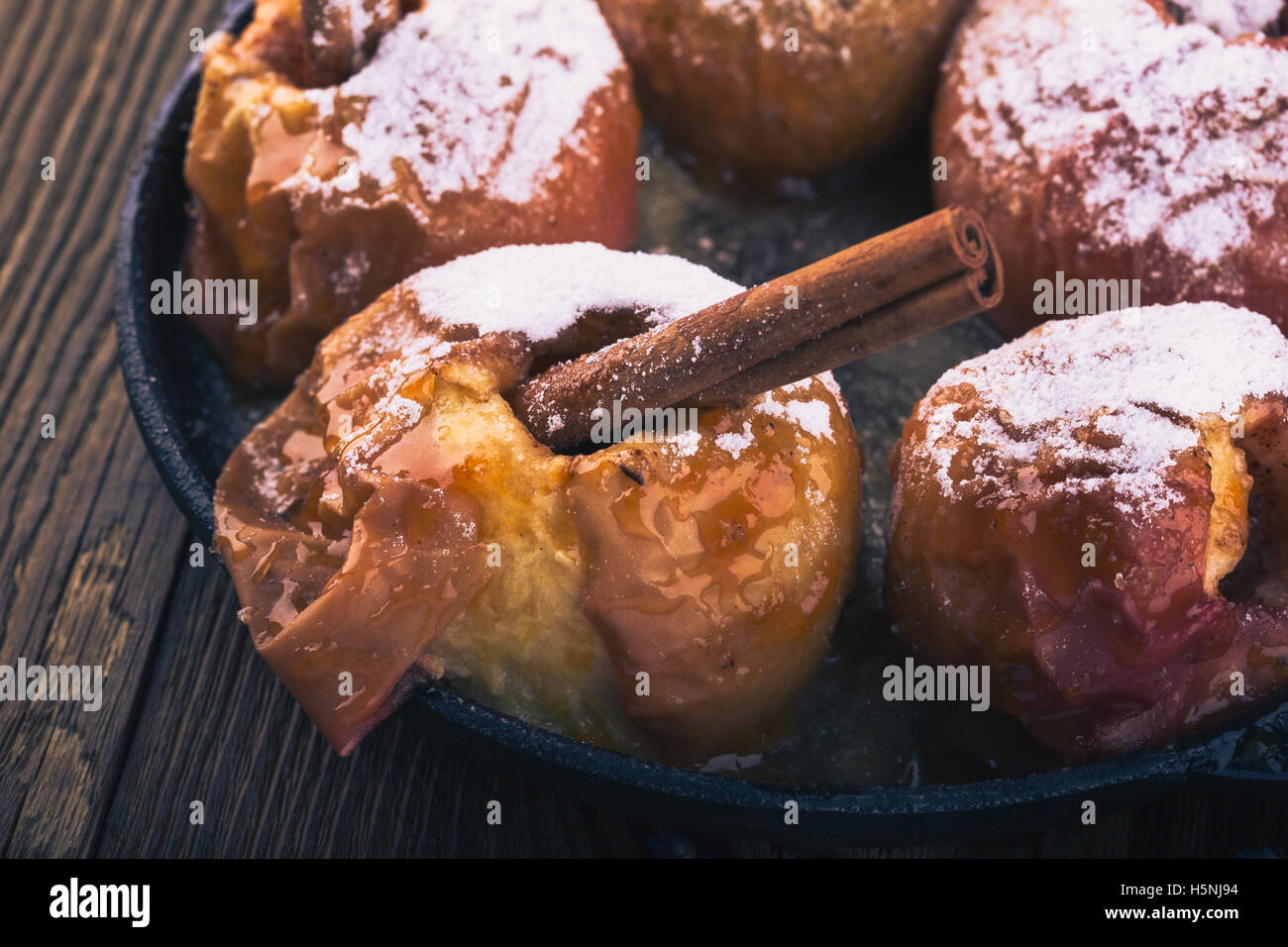 Homemade caramelized baked apples with cinnamon sticks in frying pan on ...
