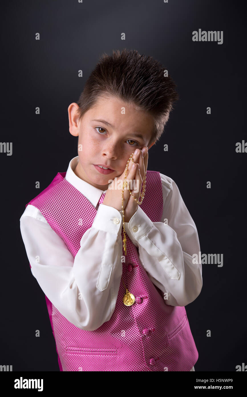 Young boy celebrating his First Holy Communion holding his rosary and ...