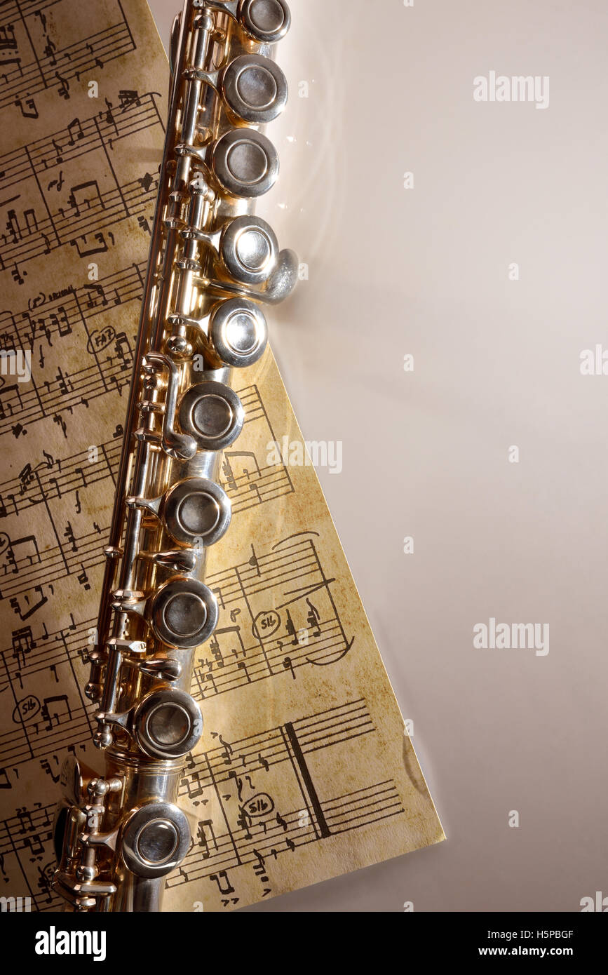 Flute and handwritten sheet music on white table. Vertical composition ...