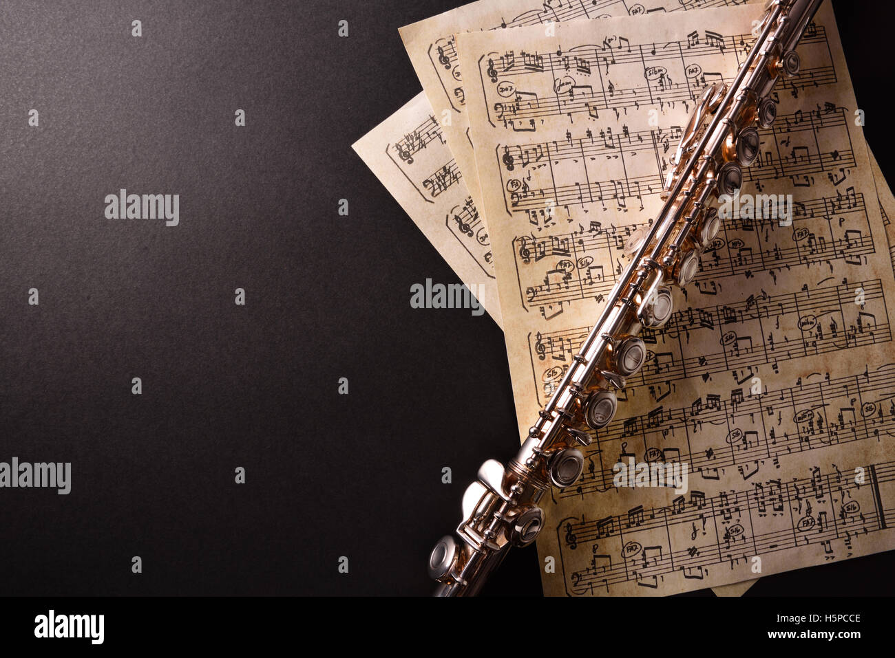 Transverse flute and old sheet music on black table. Horizontal ...