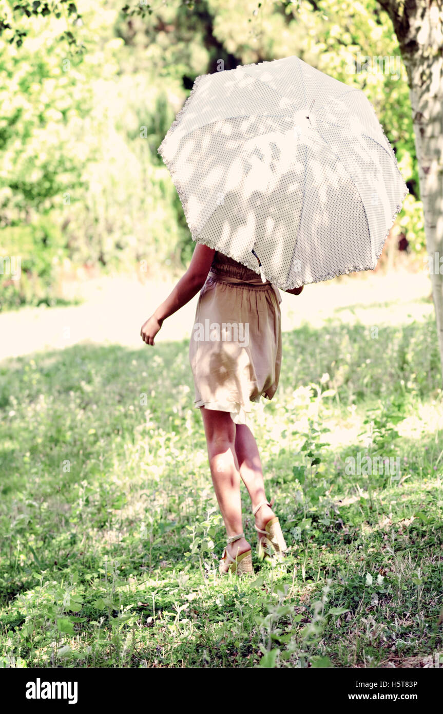 Young woman with umbrella in meadow, rear view Stock Photo - Alamy