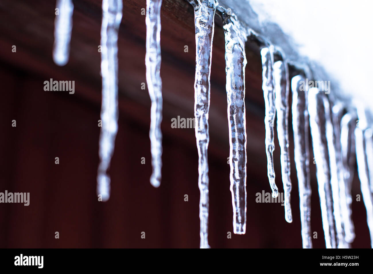 Some ice drops is melting down in the sun at the top of the red roof ...