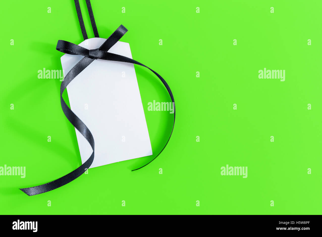 White tag with black ribbon on green background Stock Photo - Alamy