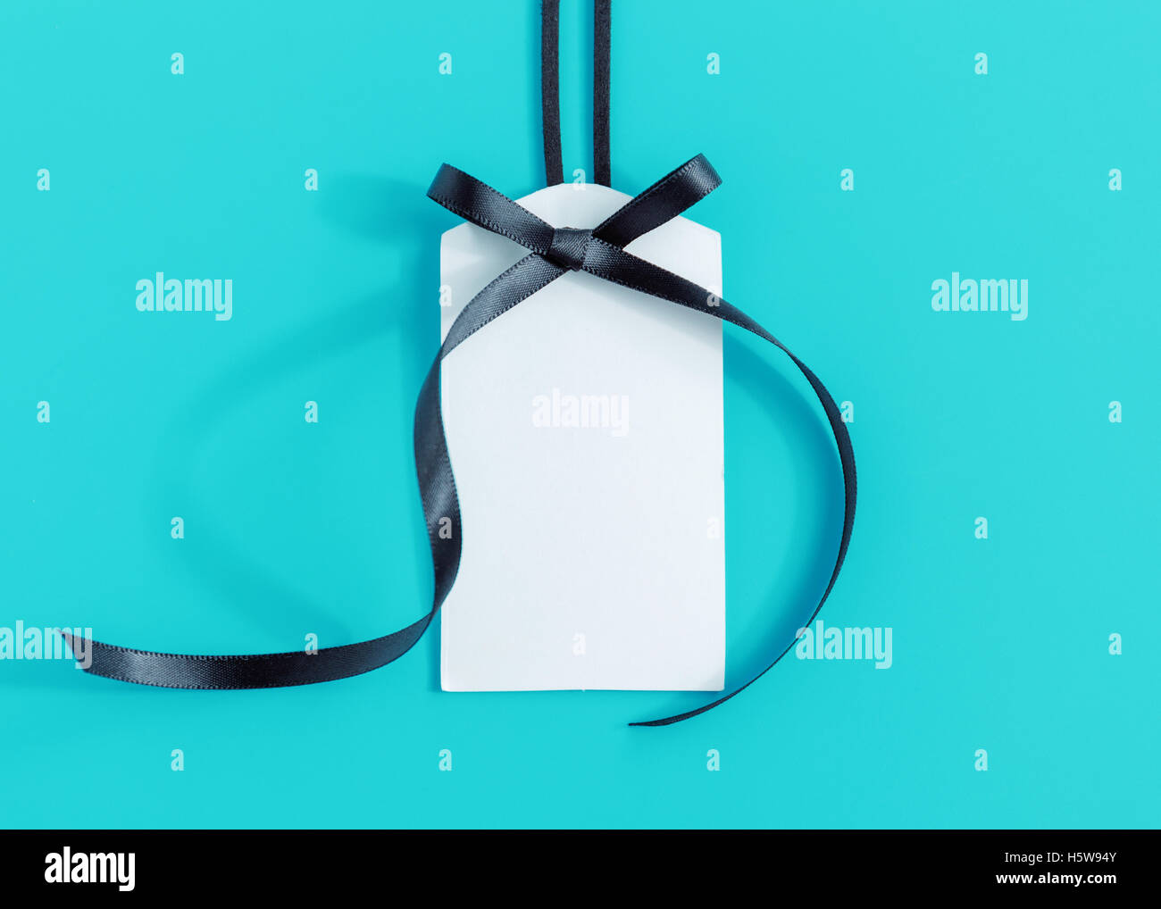 Gift tag with ribbon on blue background Stock Photo - Alamy