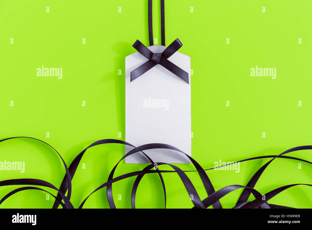 Gift tag with black ribbon on green background Stock Photo - Alamy