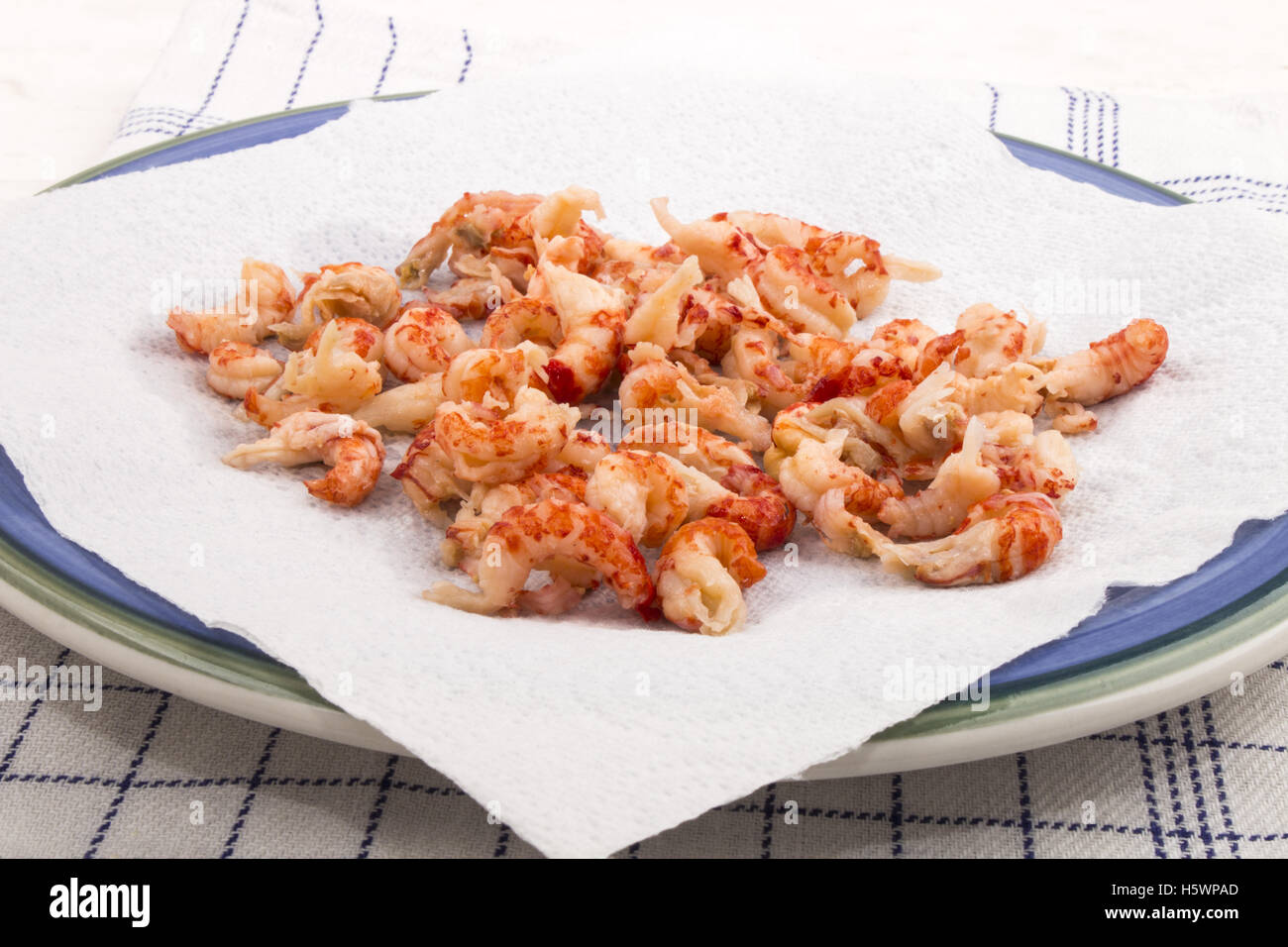 cleaned and cooked crayfish tails with white kitchen paper on a blue ...