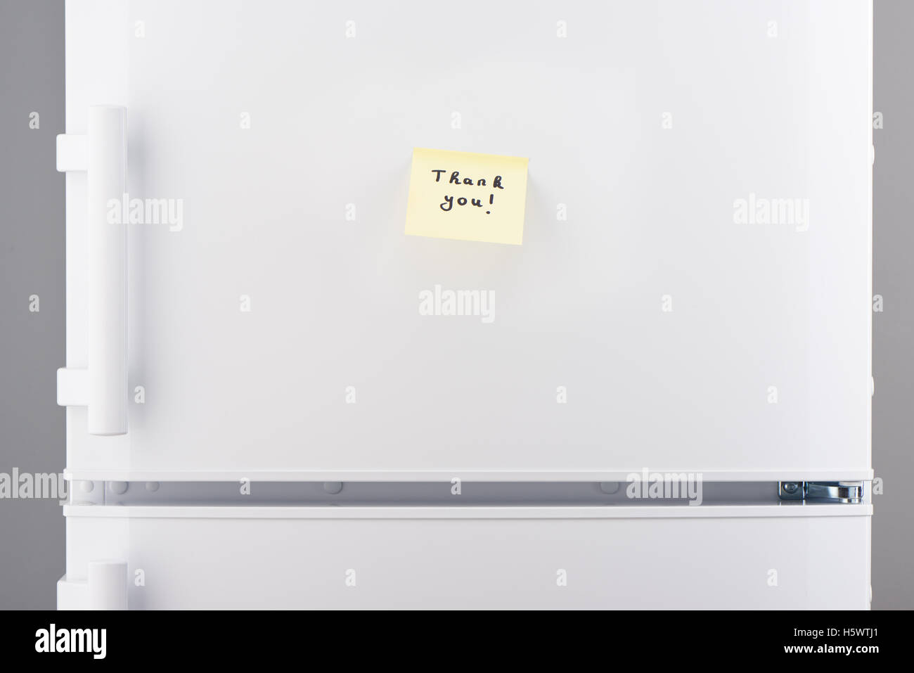Thank you note on light yellow sticky paper on white refrigerator door ...