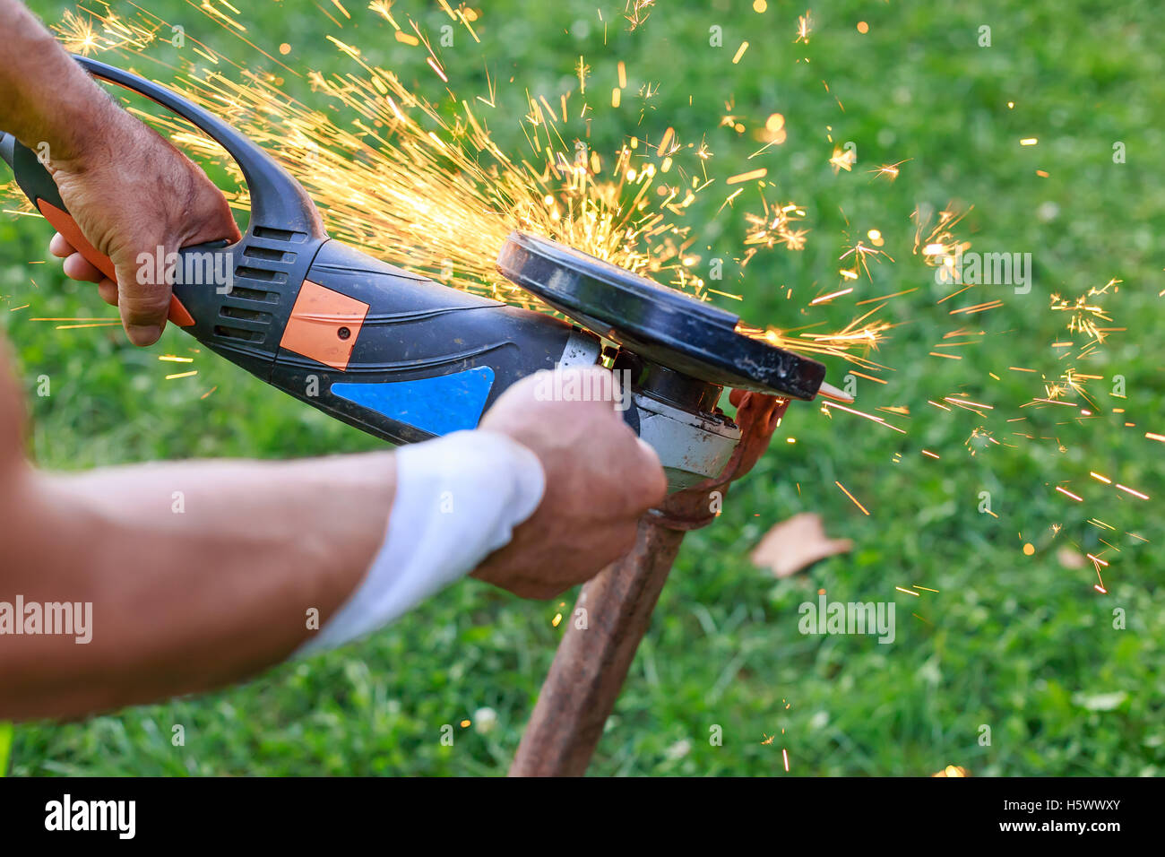 Injured worker hands cutting metal with grinder. Sparks while grinding ...