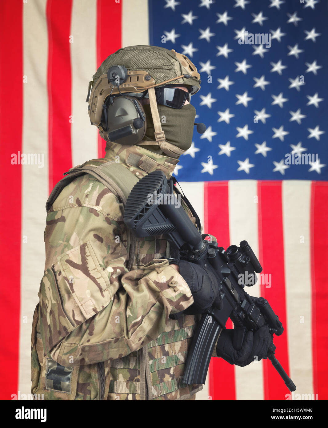 US soldier with American flag on background and machine gun in hands ...
