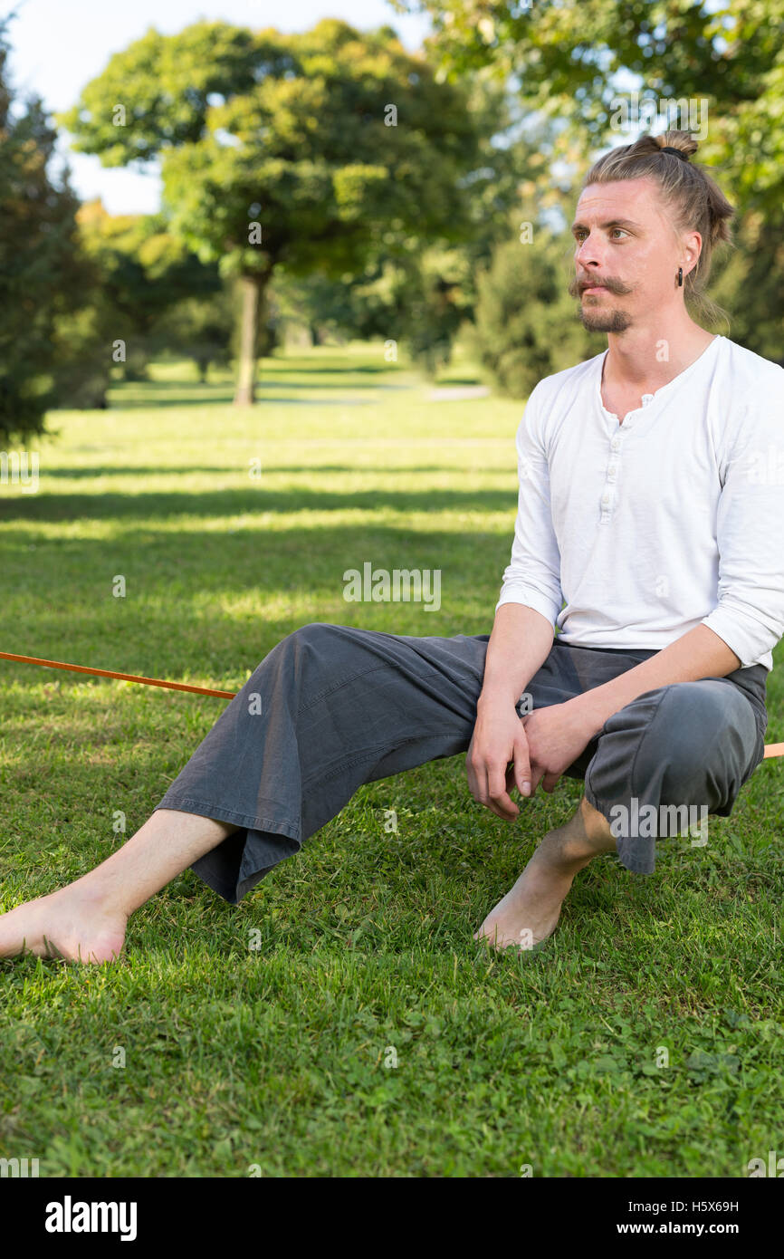 portrait of man sitting on slackline and balancing on a rope Stock ...
