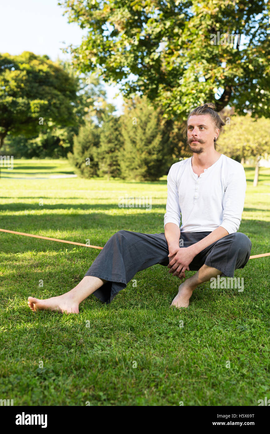 portrait of man sitting on slackline and balancing on a rope Stock ...