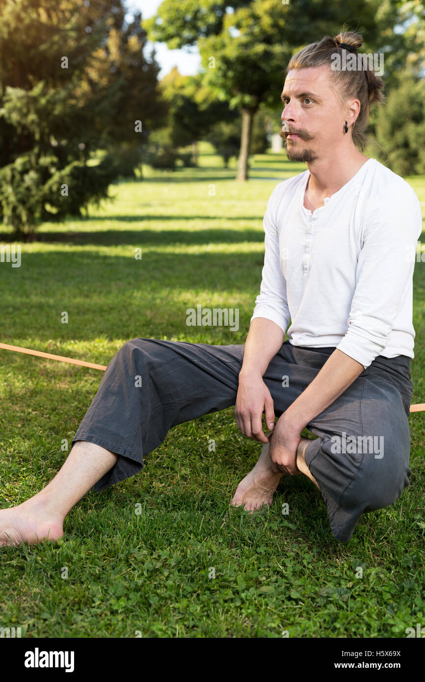 portrait of man sitting on slackline and balancing on a rope Stock ...