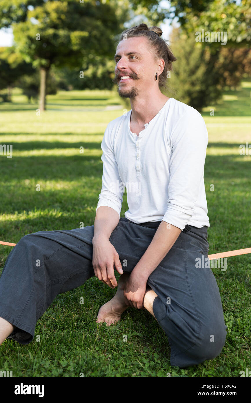 portrait of man sitting on slackline and balancing on a rope Stock ...