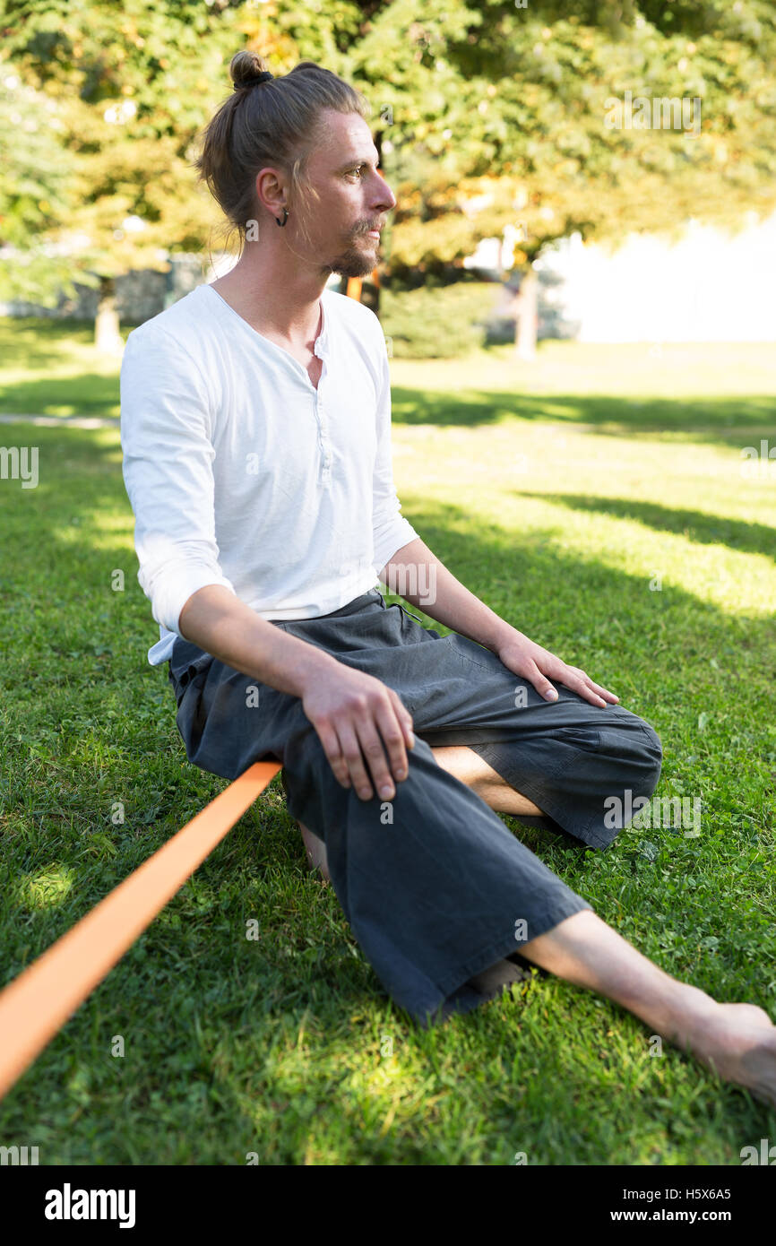 portrait of man sitting on slackline and balancing on a rope Stock ...
