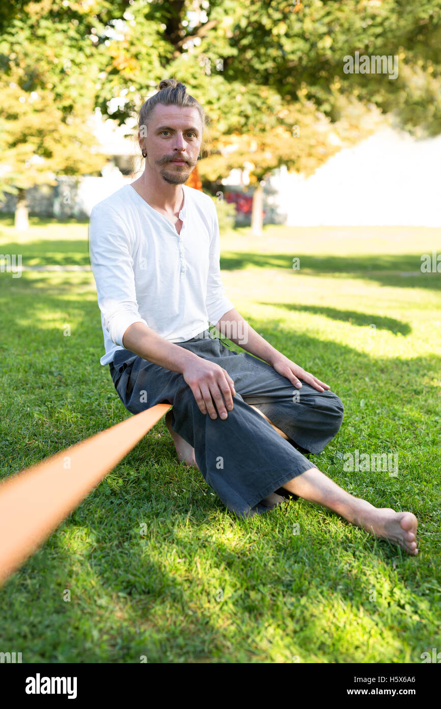 portrait of man sitting on slackline and balancing on a rope Stock ...