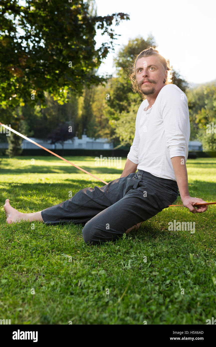 portrait of man sitting on slackline and balancing on a rope Stock ...