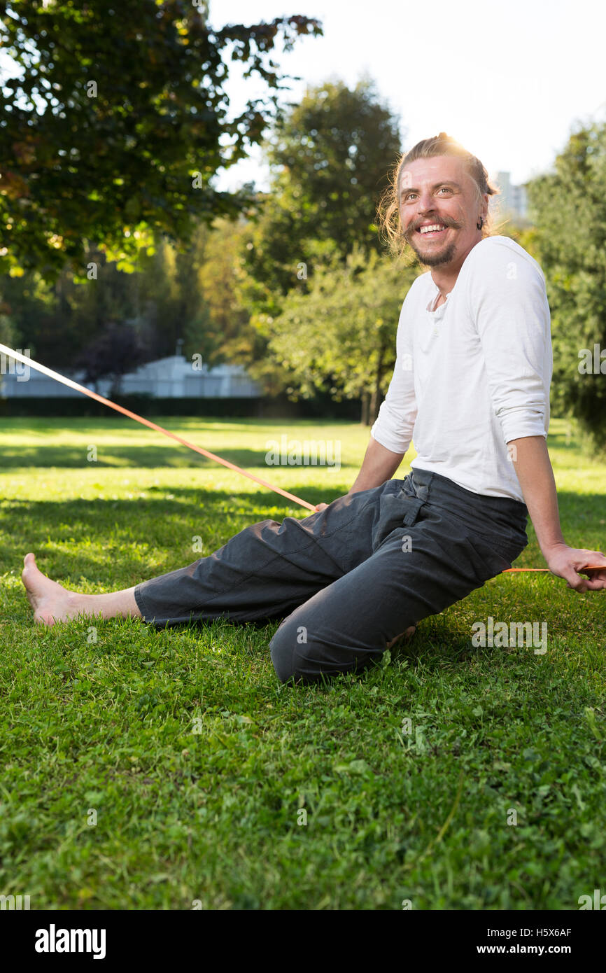 portrait of man sitting on slackline and balancing on a rope Stock ...