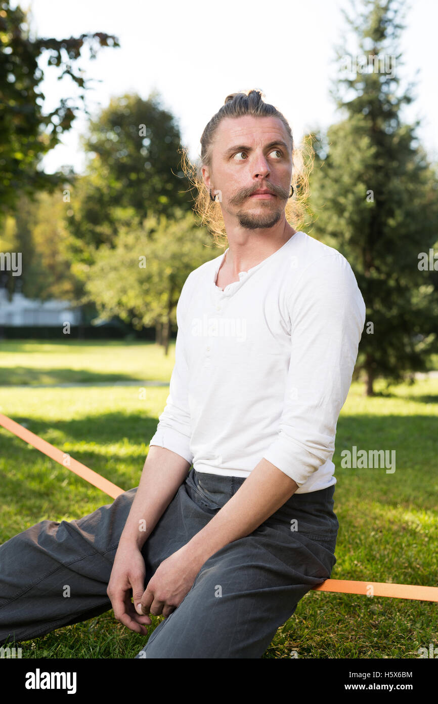 portrait of man sitting on slackline and balancing on a rope Stock ...