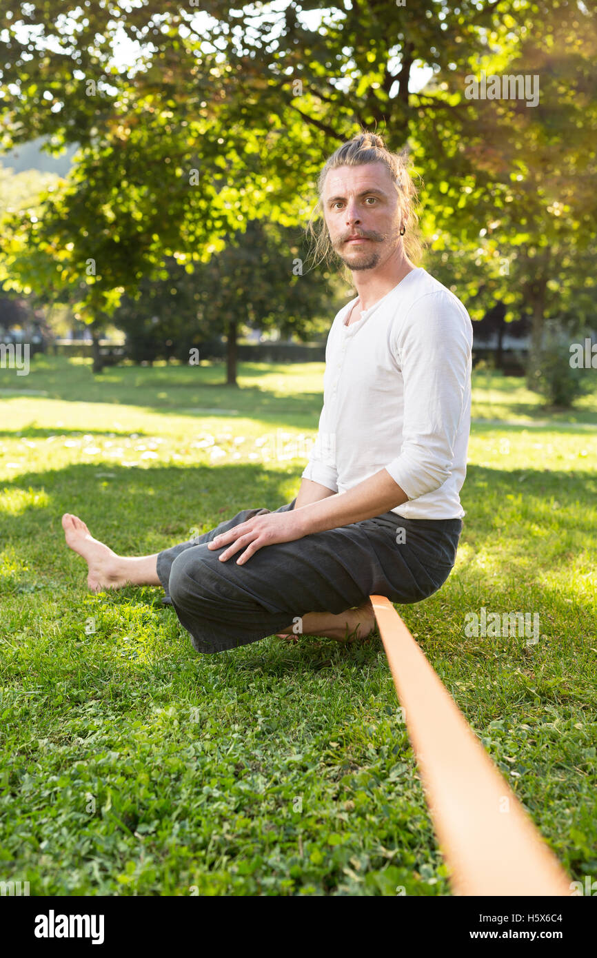 portrait of man sitting on slackline and balancing on a rope Stock ...