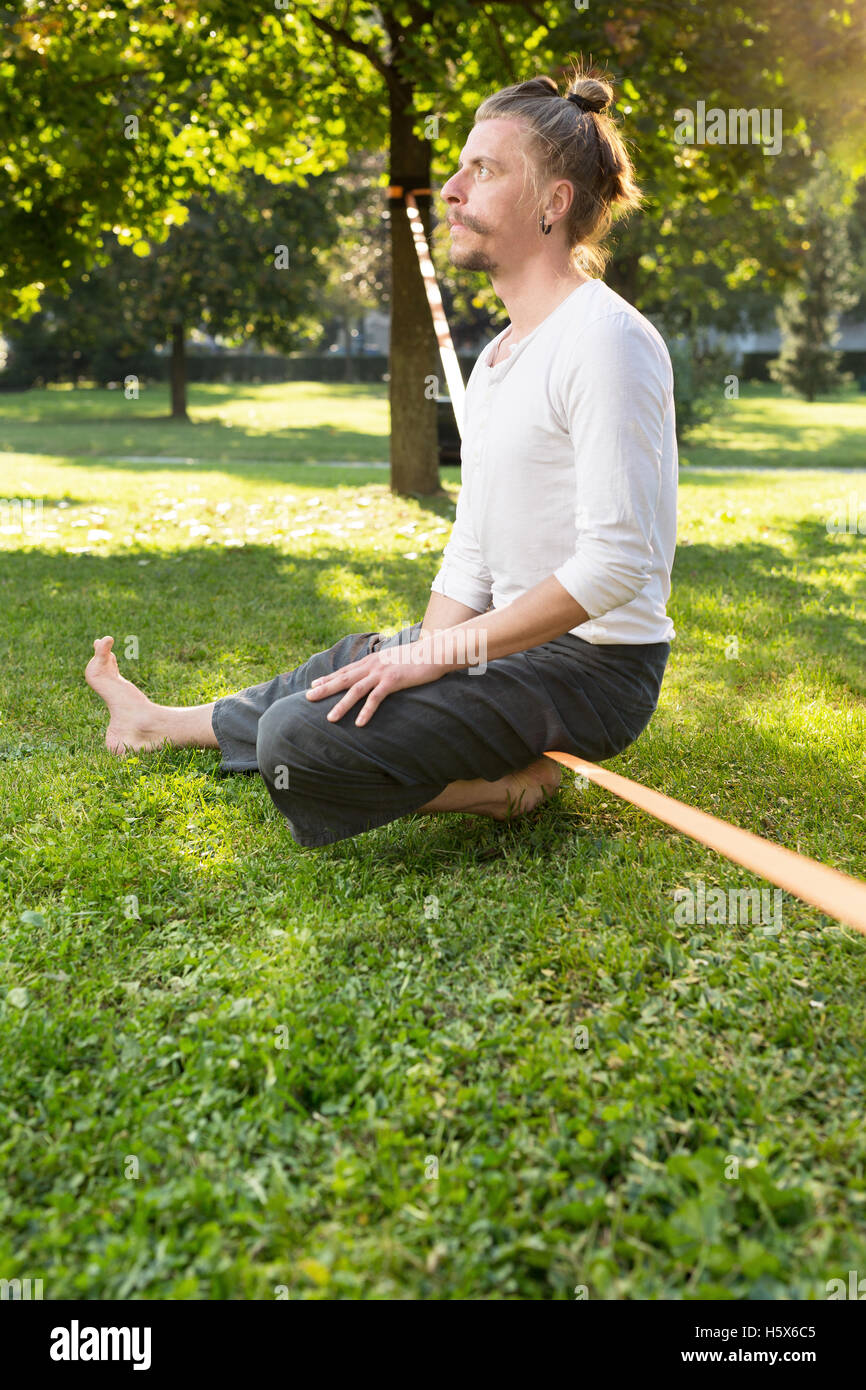 portrait of man sitting on slackline and balancing on a rope Stock ...