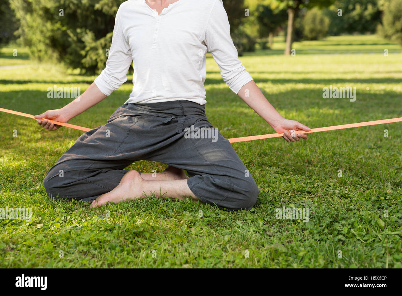 portrait of man sitting on slackline and balancing on a rope Stock ...