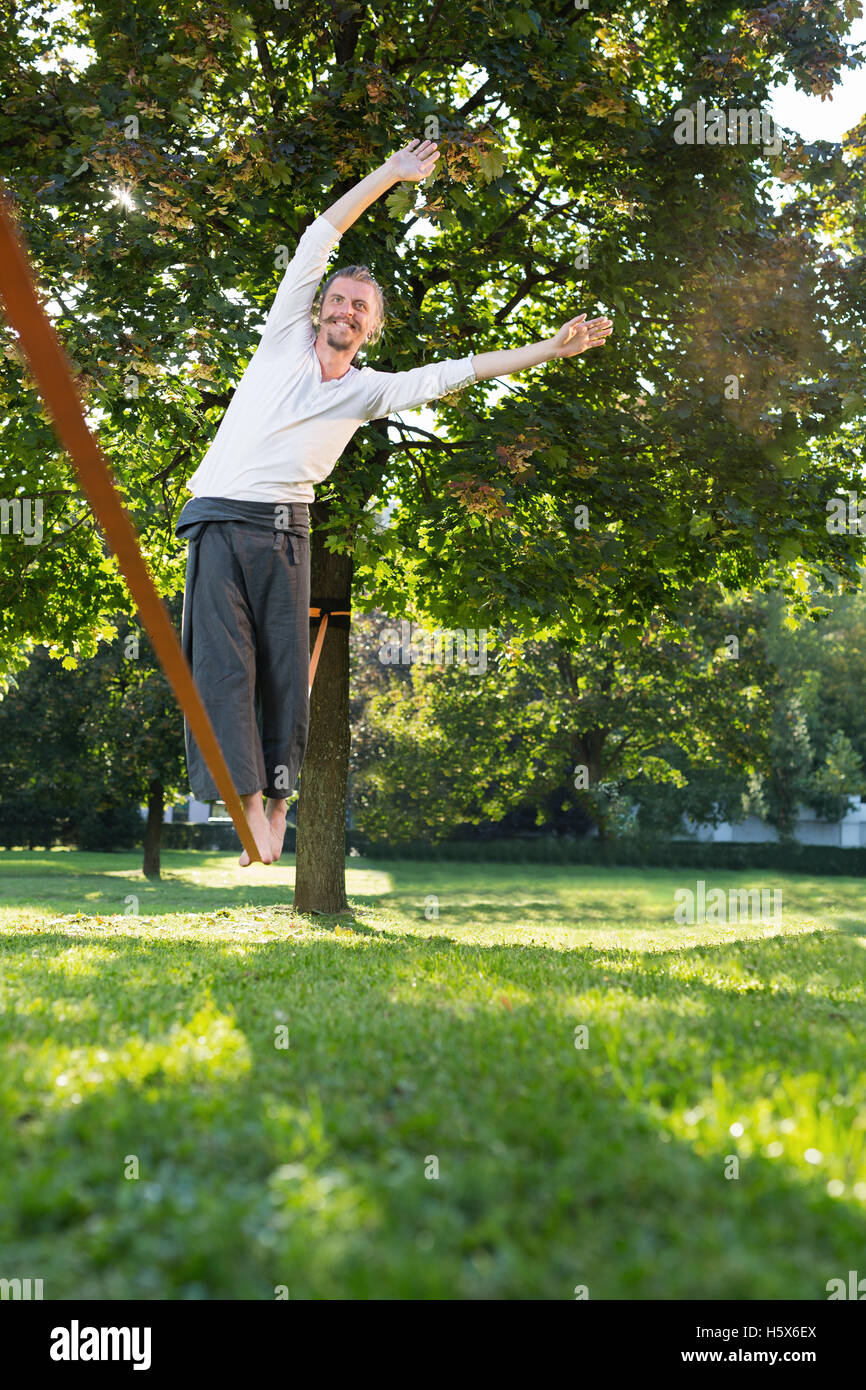 Portrait of handsome young man walking on slackline in the park Stock ...